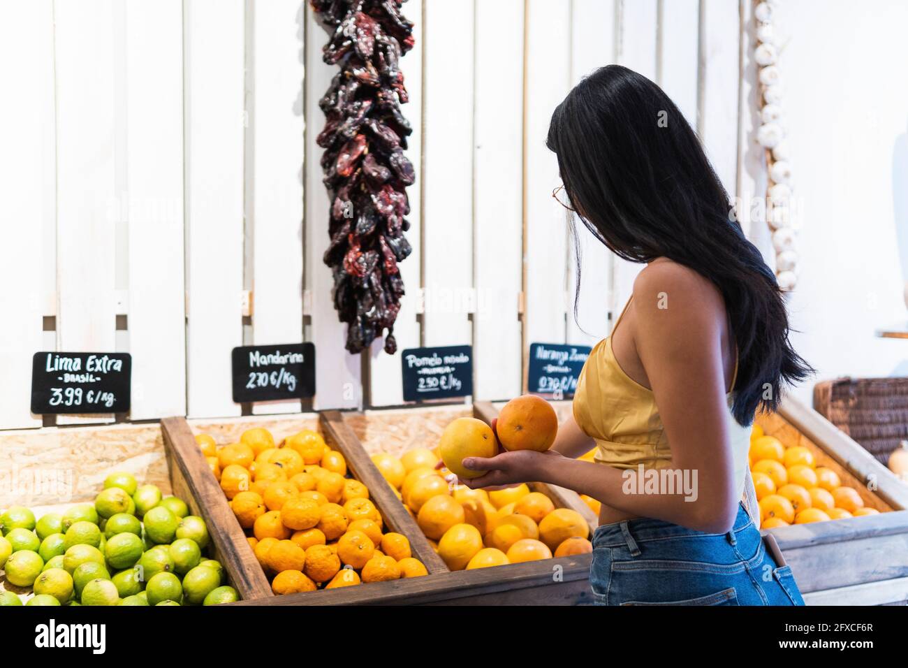 Young woman with long hair buying oranges at grocery store Stock Photo ...
