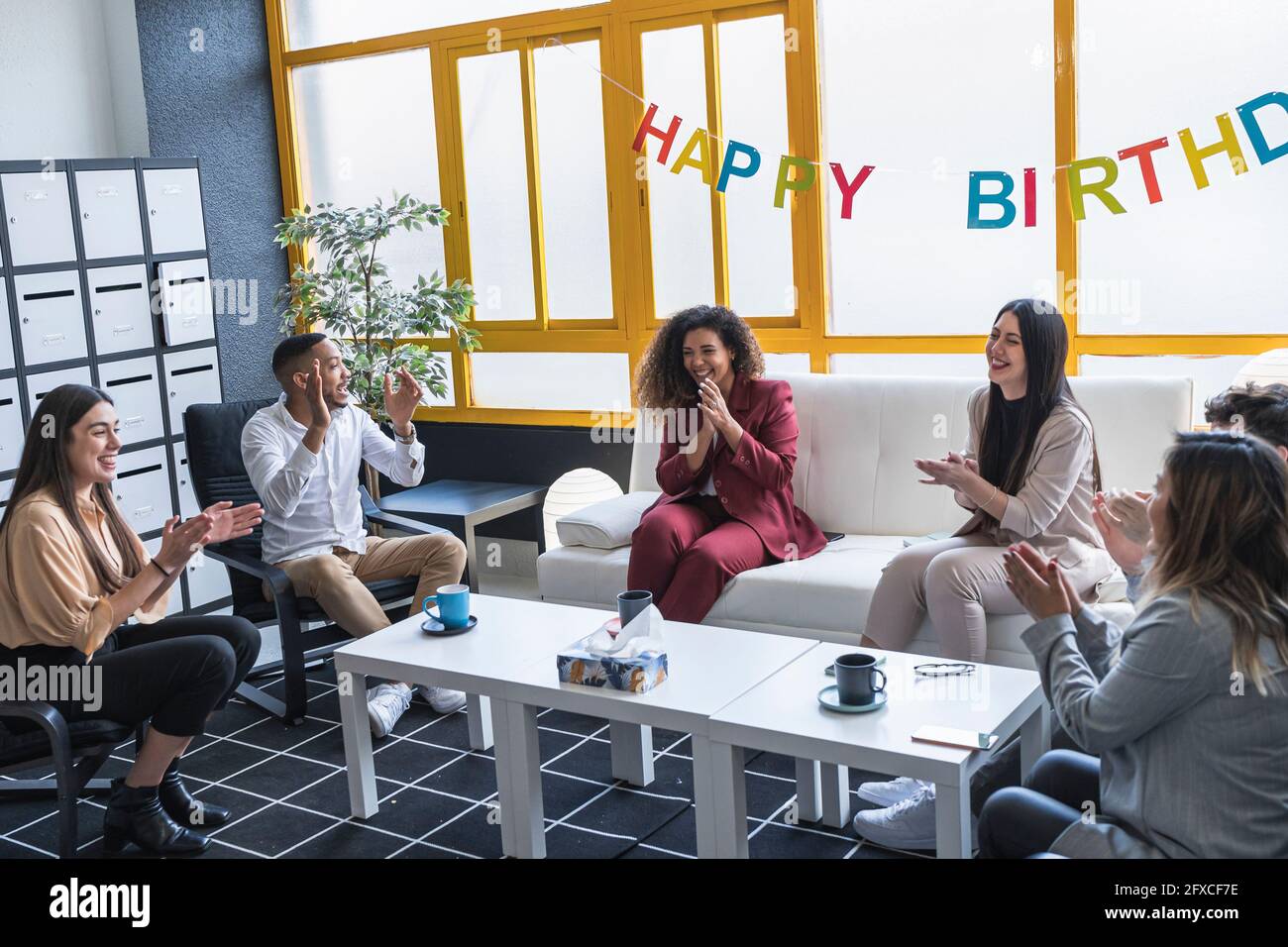 Happy male and female professionals clapping during birthday ...