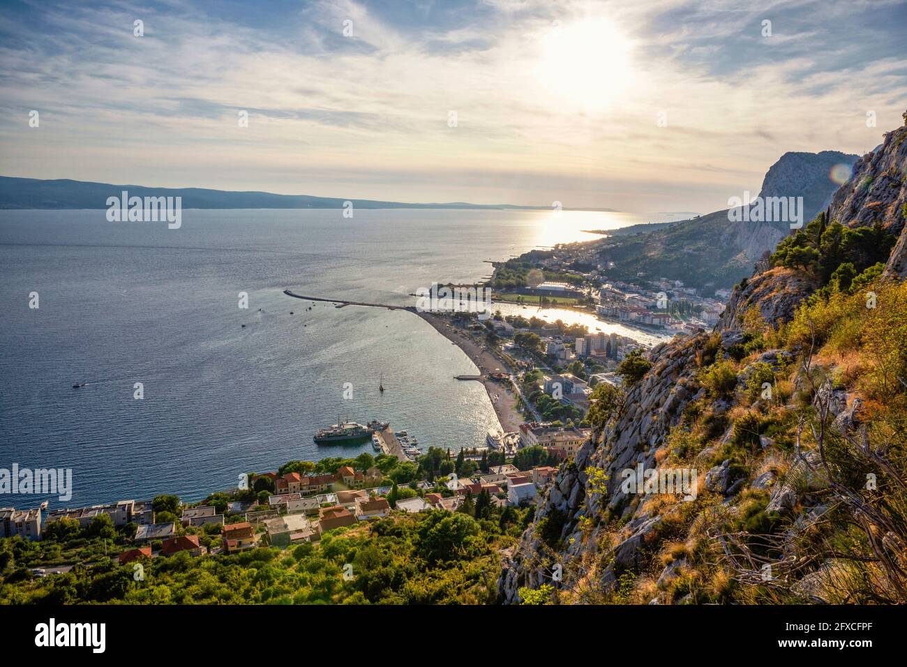 Croatia, Split-Dalmatia County, Omis, Sun setting over coastal town situated at confluence of ...