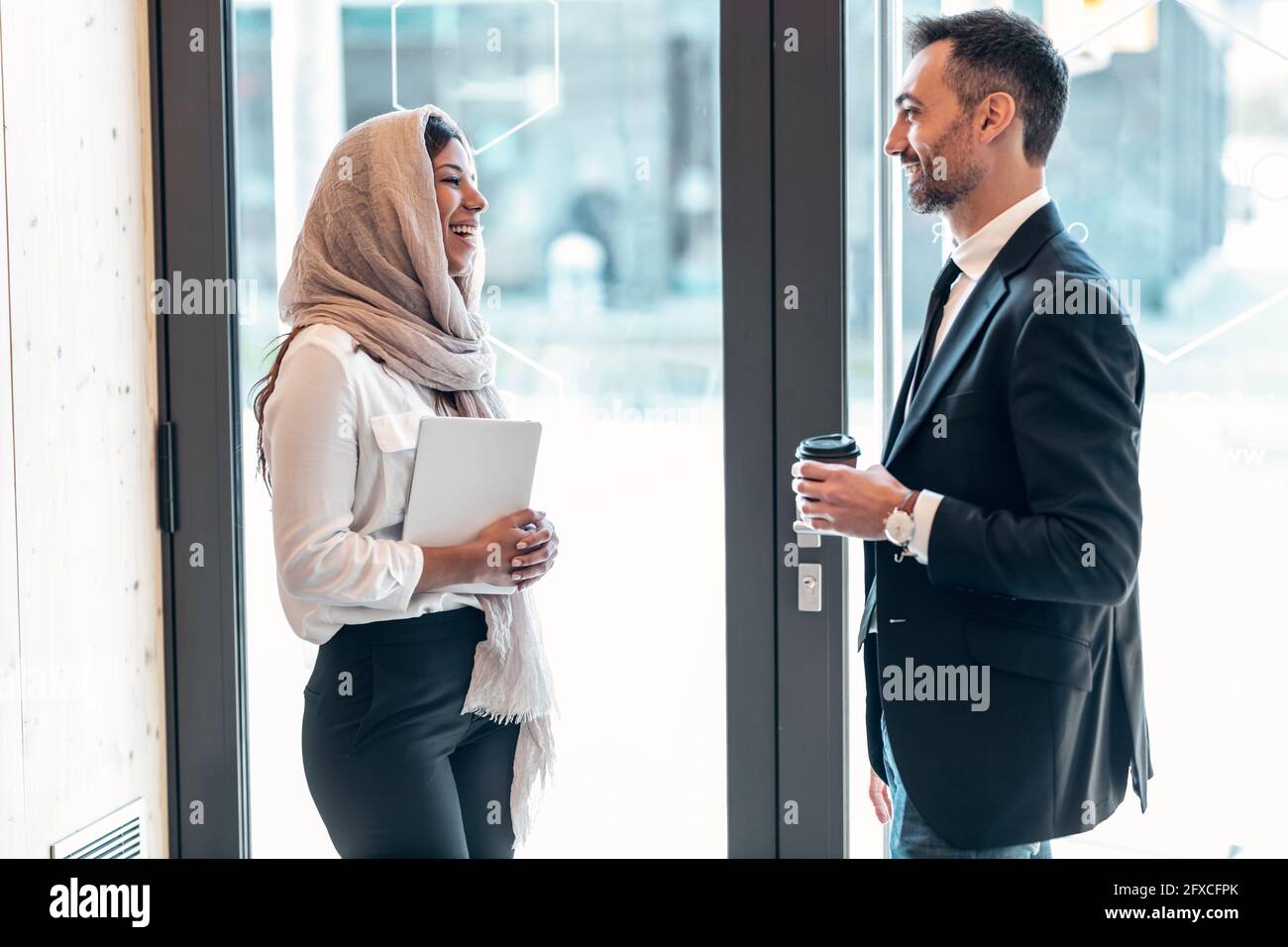 Smiling male and female business professionals standing face to face at ...