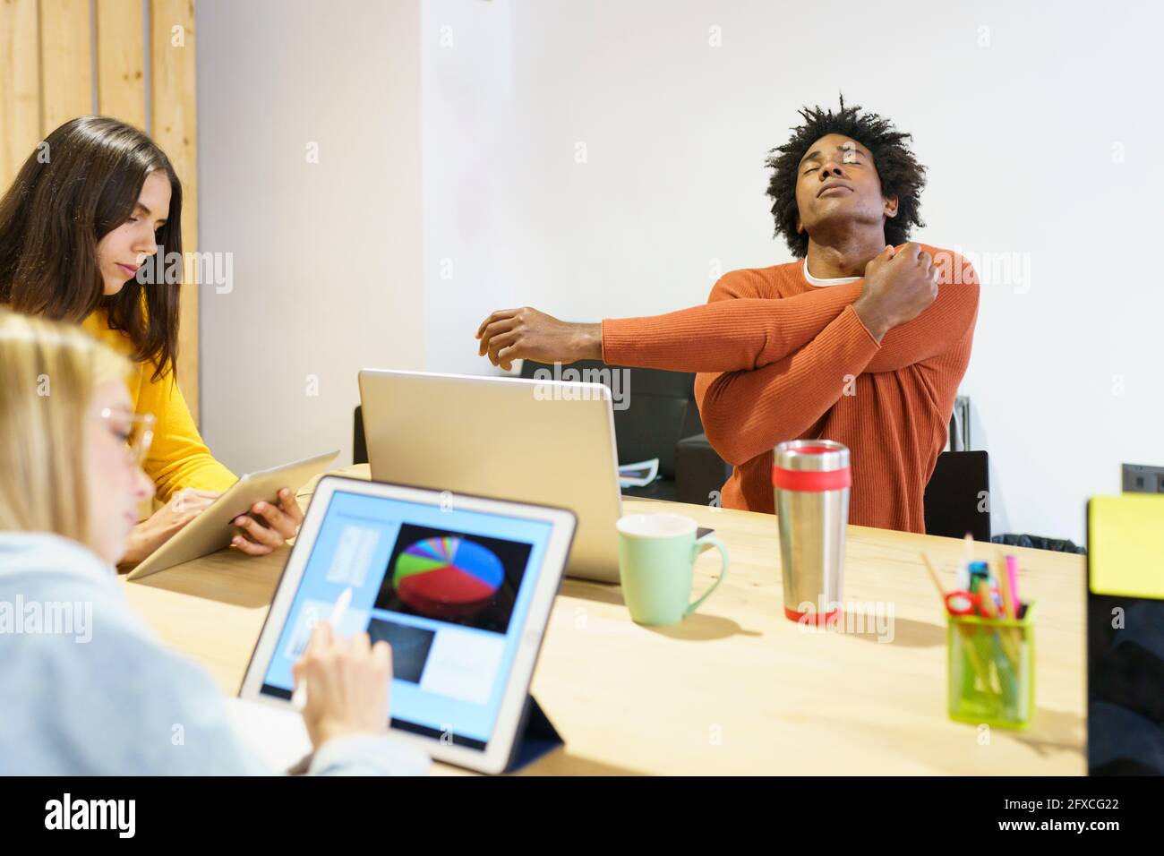 Creative businessman stretching at table in office Stock Photo - Alamy