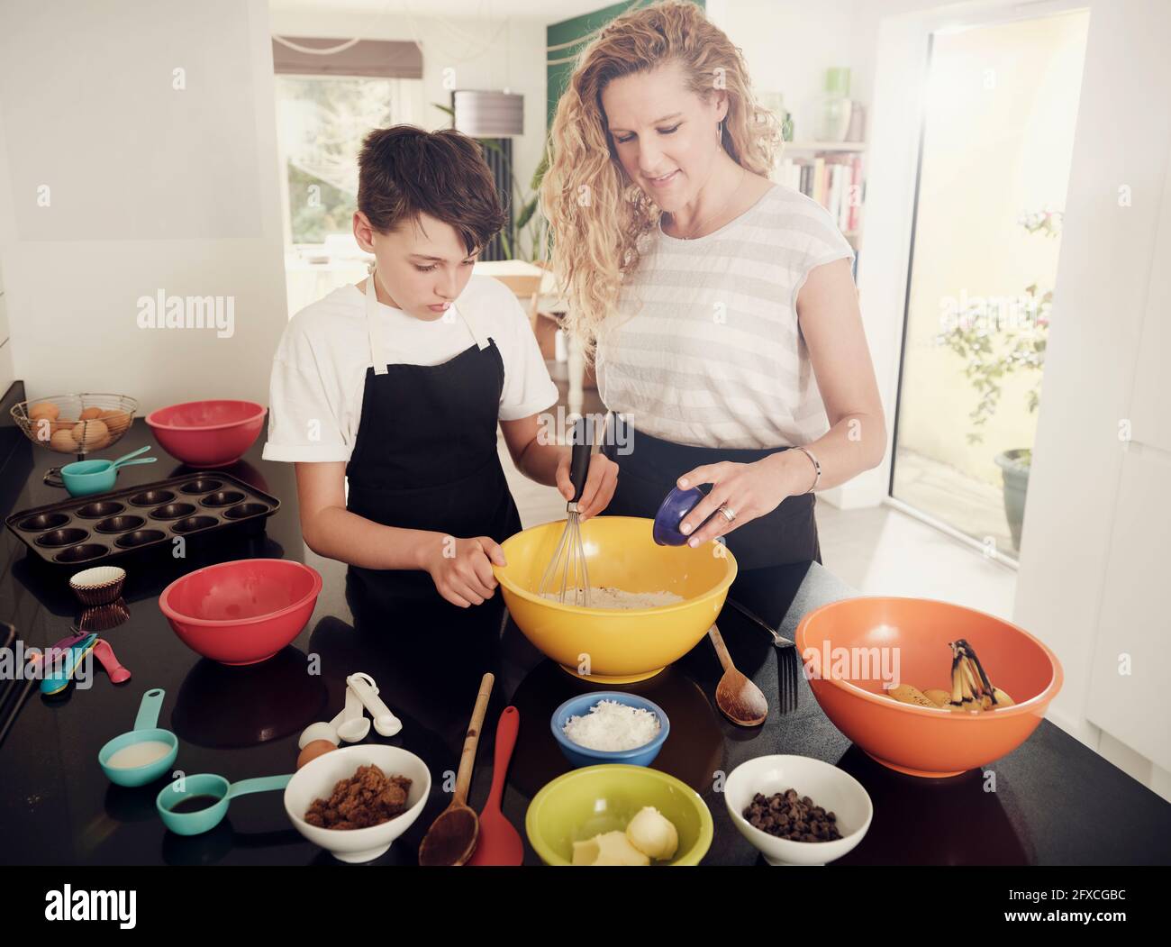 Son mixing ingredient with mother in kitchen at home Stock Photo - Alamy