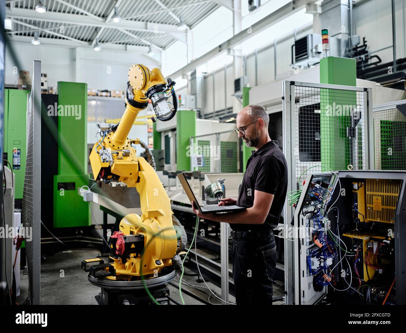 Male engineer using laptop by robotic arm Stock Photo - Alamy