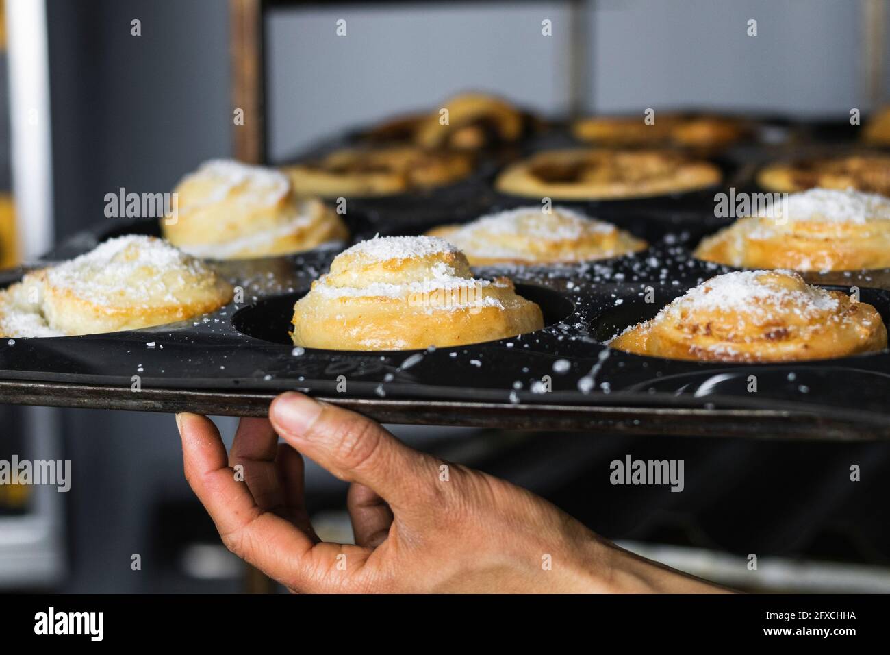 Female baker holding tray of cinnamon buns in kitchen Stock Photo - Alamy