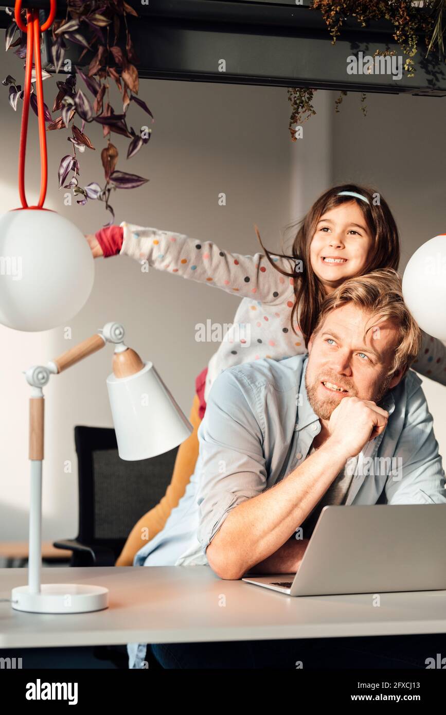 Smiling daughter piggybacking on thoughtful father at home Stock Photo ...