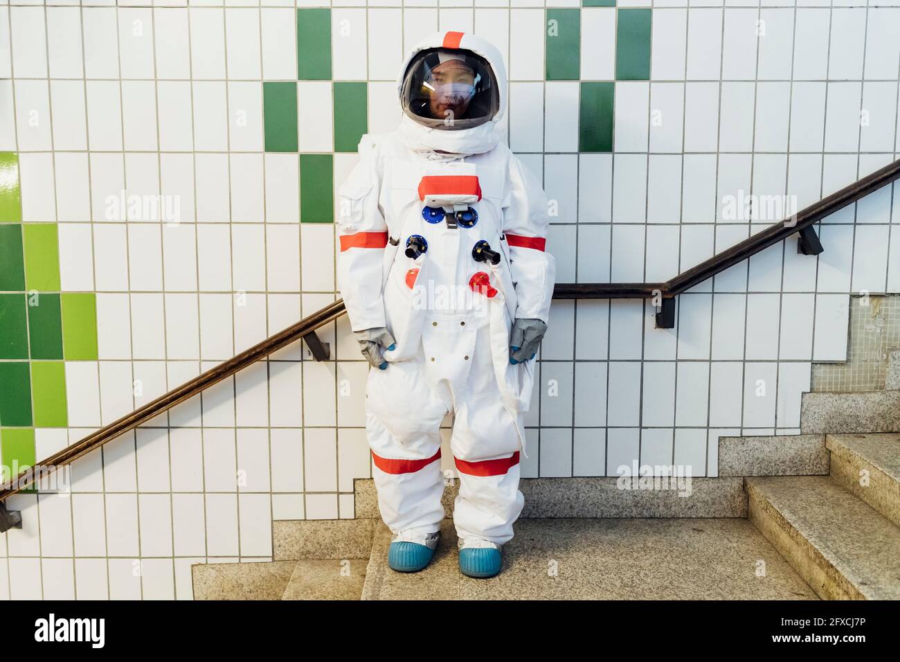 Young female astronaut in space suit standing by wall in subway Stock ...