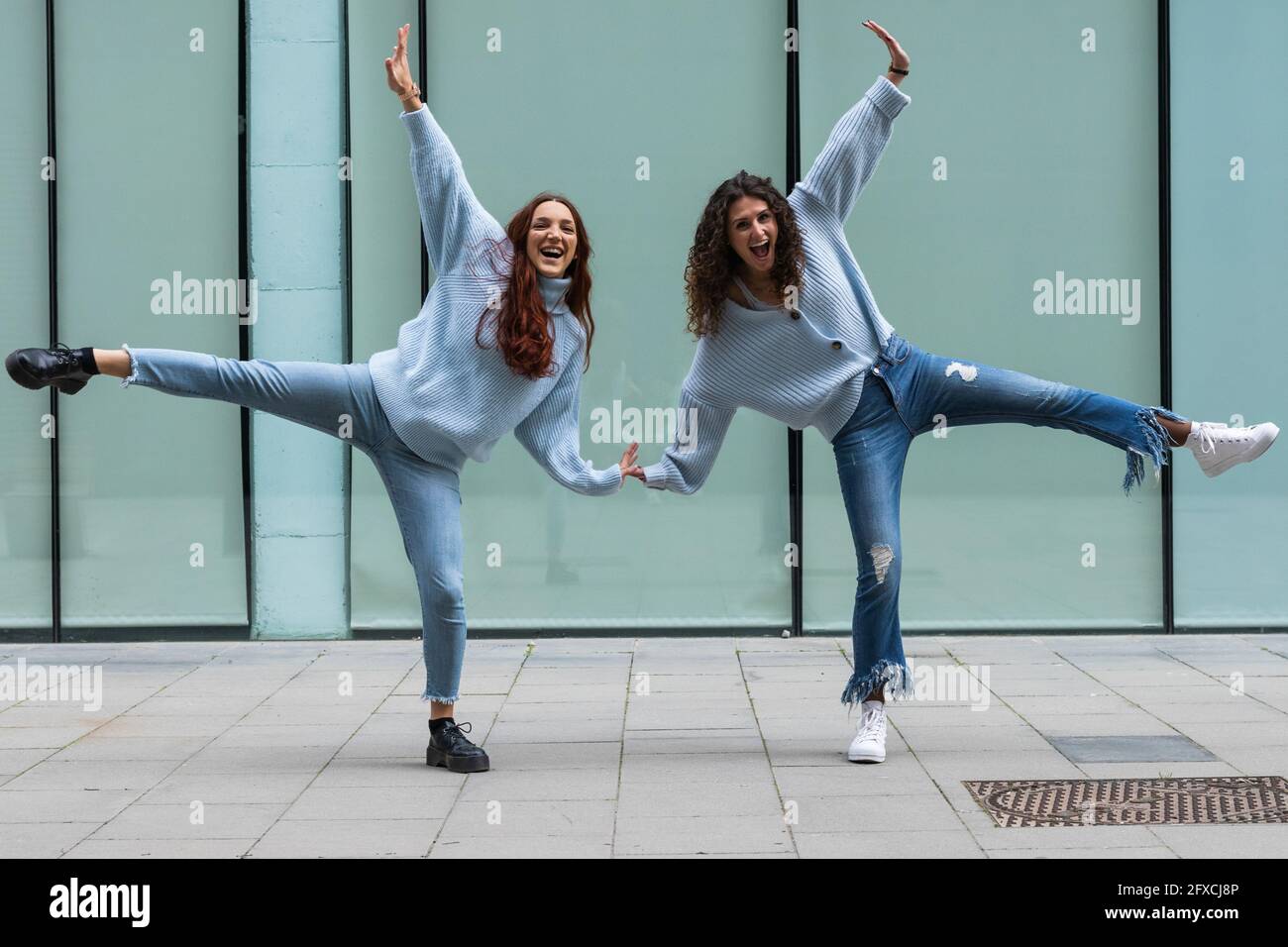 Carefree friends standing on one leg in front of wall Stock Photo - Alamy
