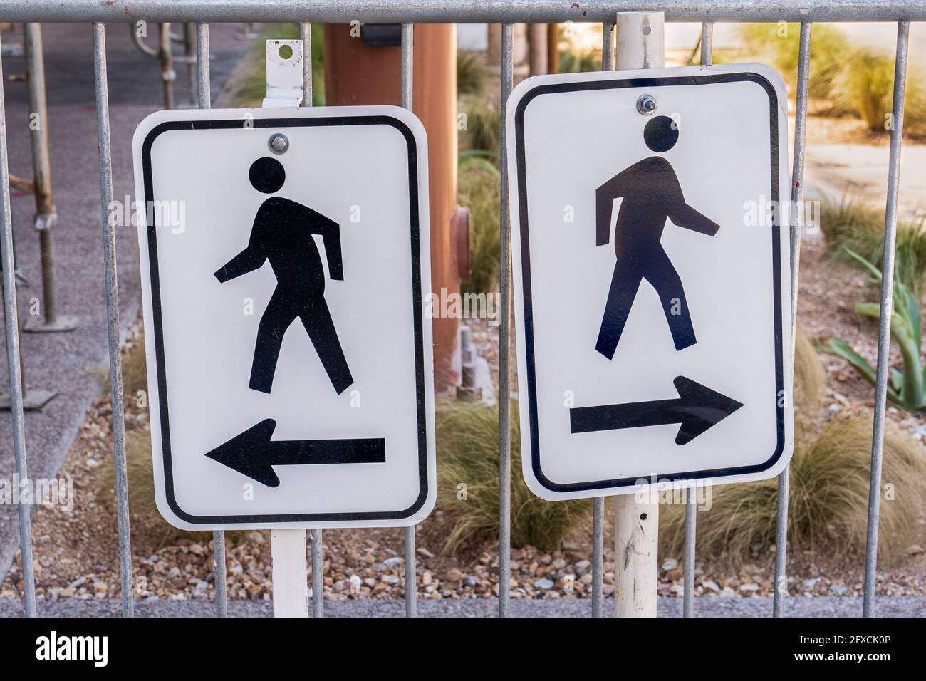 two street signs directing pedestrains to walk this way each pointing ...