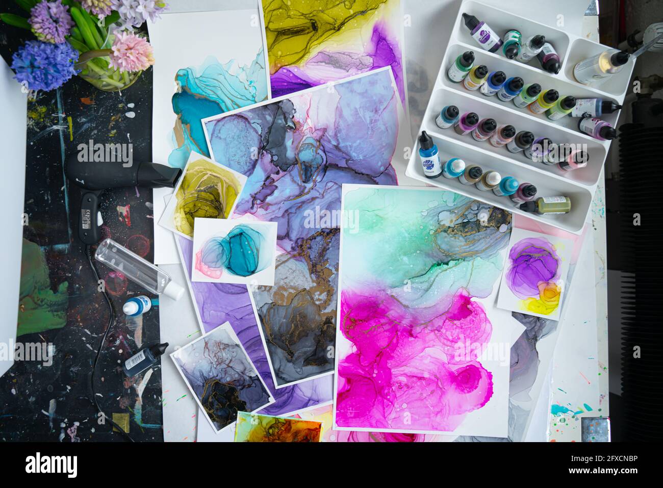 Table clutter in a creative studio. Alcohol Ink Painting. Above shot ...