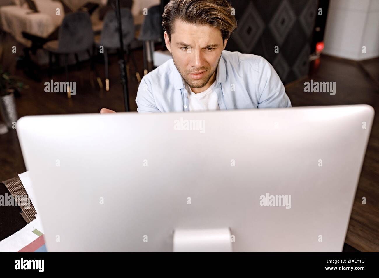 Confused young Caucasian male worker freelancer look at computer screen ...