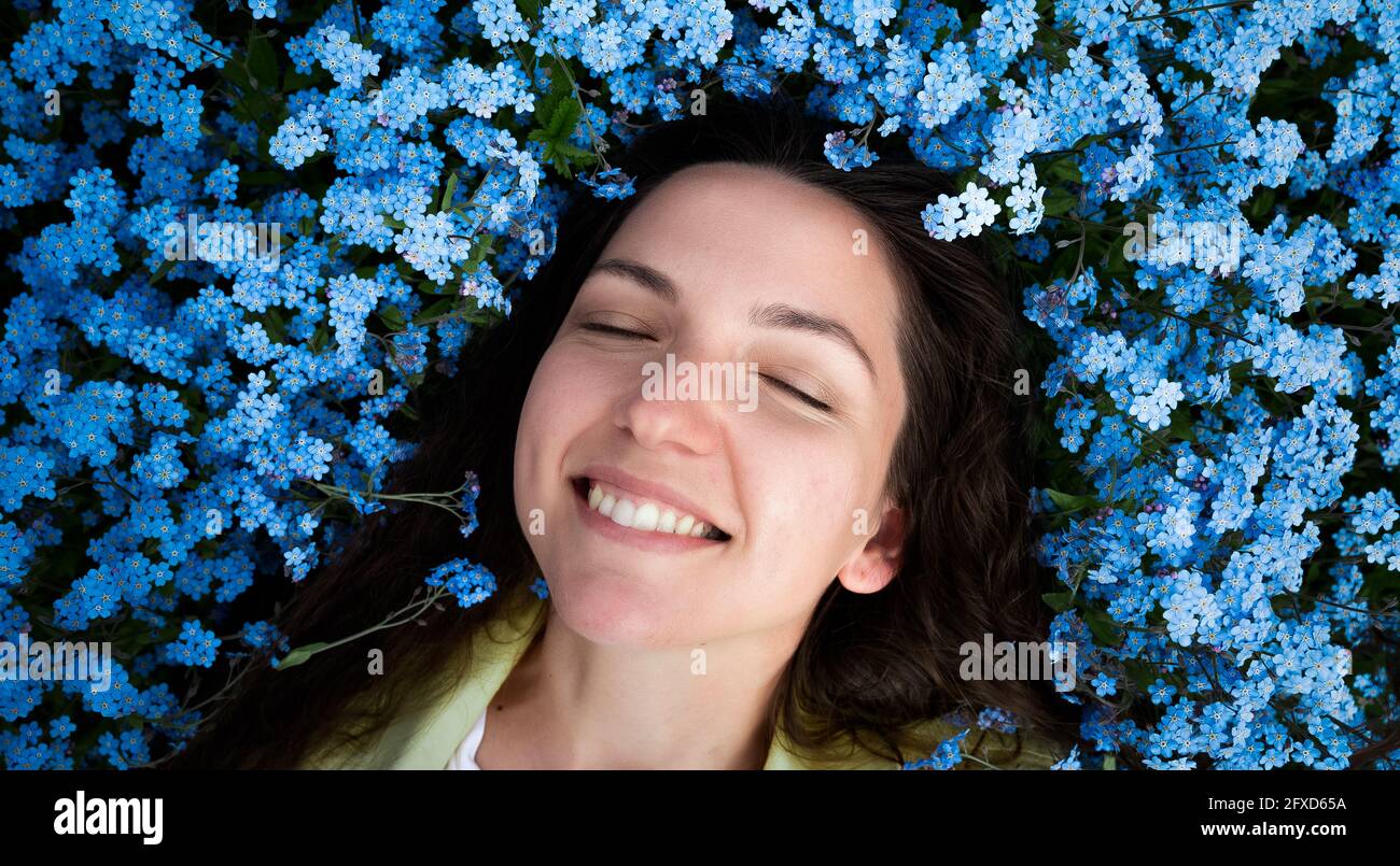 Beautiful young girl smiling on a background of blue flowers Stock ...