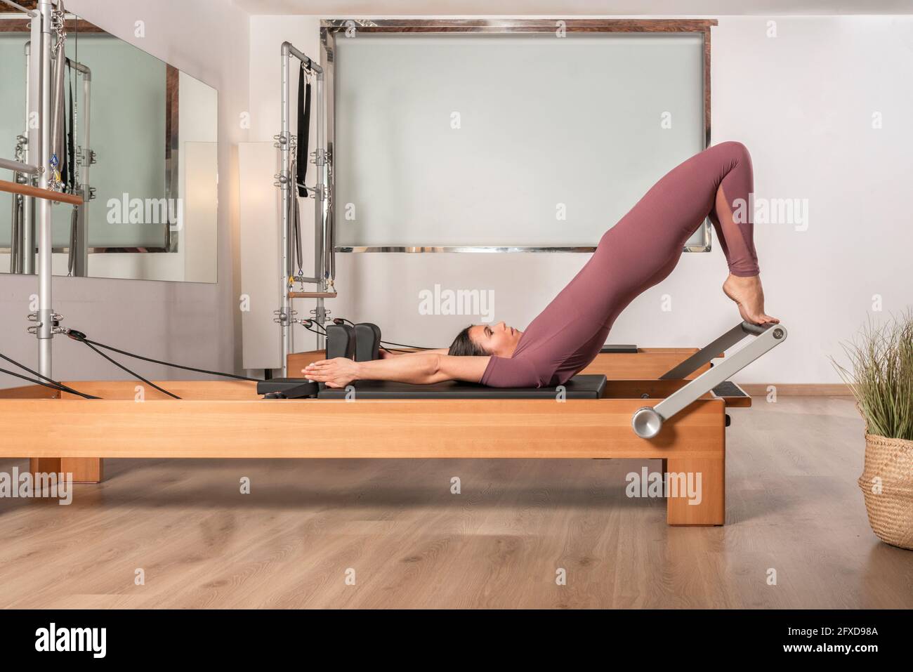 brunette girl doing the pilates shoulder bridge exercise on the reform ...