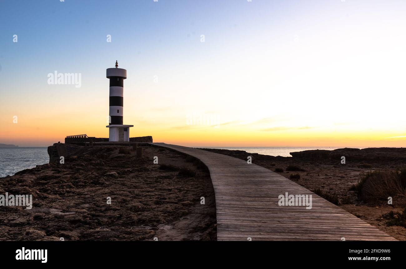 Wood walkway in foreground heading towards the lighthouse in Majorca ...