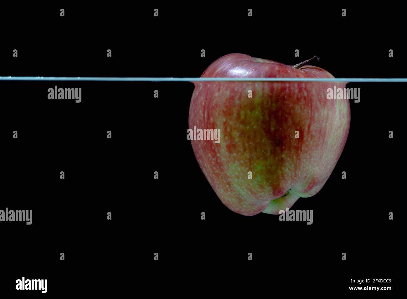 red apple floats in water on a black background, place under the text ...