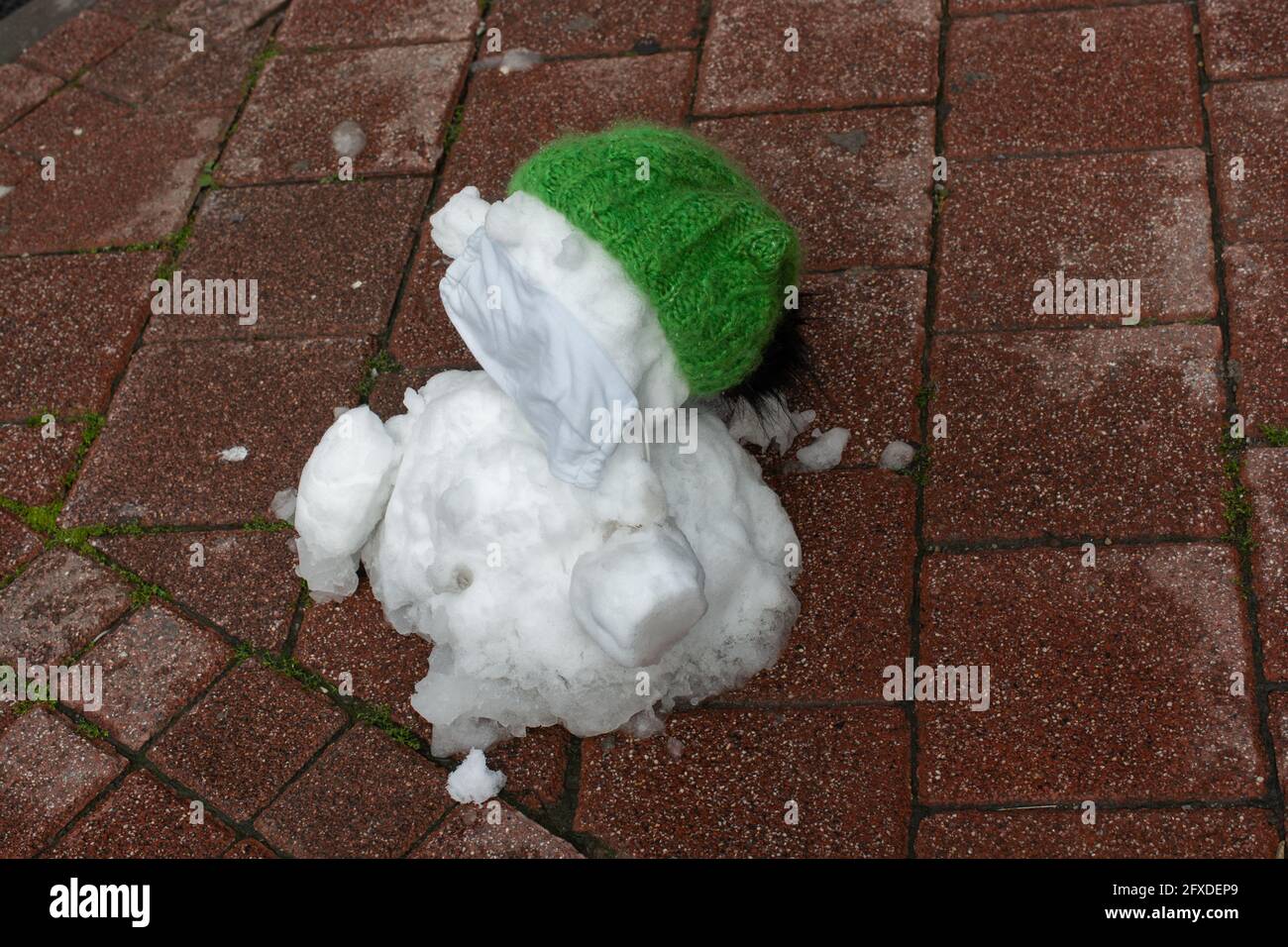 Ruined snowman in a green hat Stock Photo - Alamy