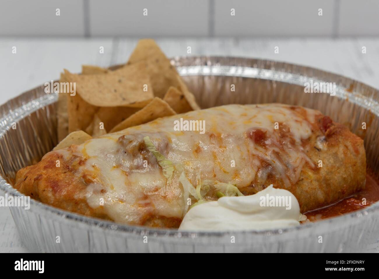 Wet burrito smothered in melted cheese and served with rice and sour ...