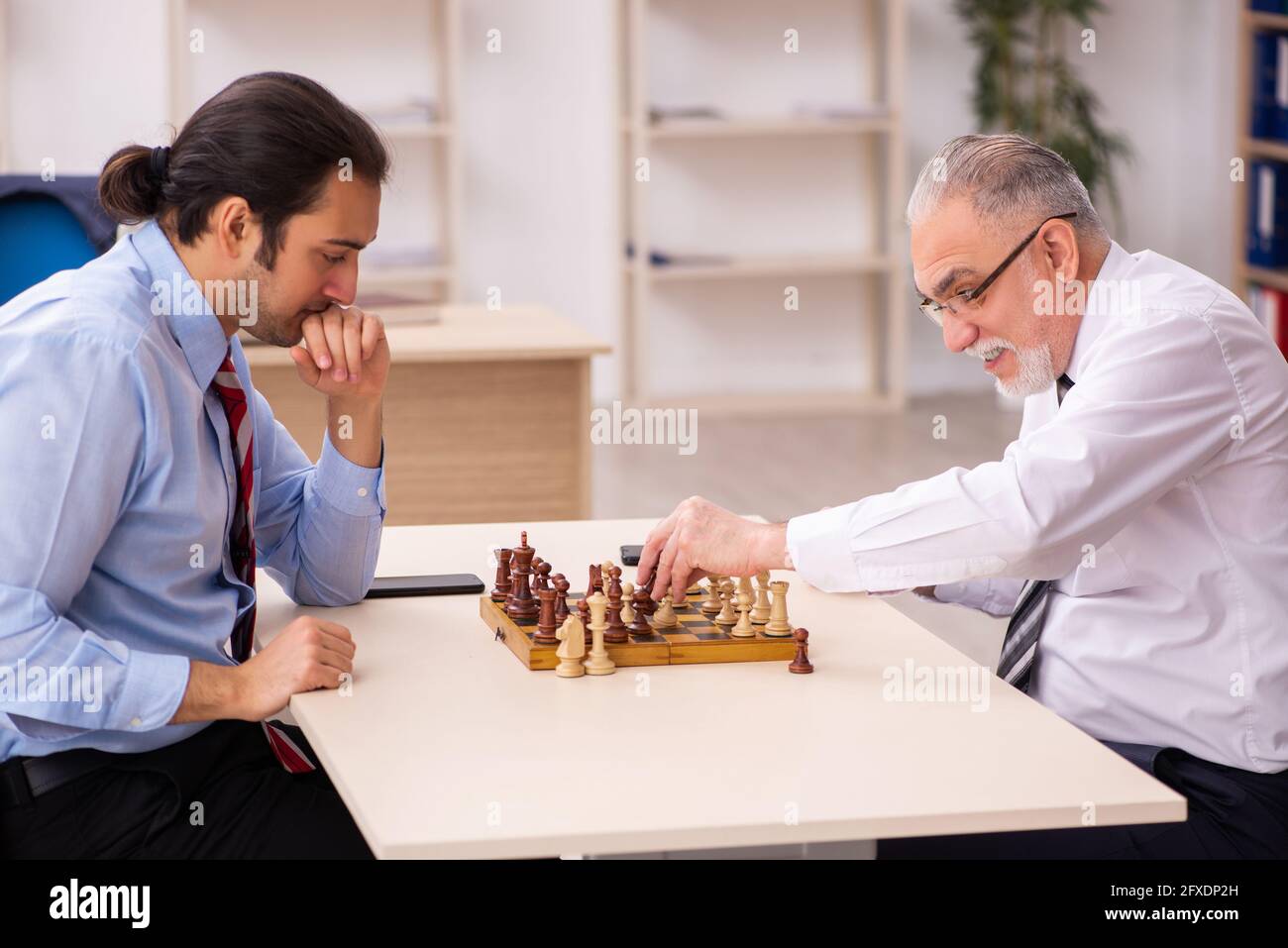 Two male employees playing chess at workplace Stock Photo - Alamy