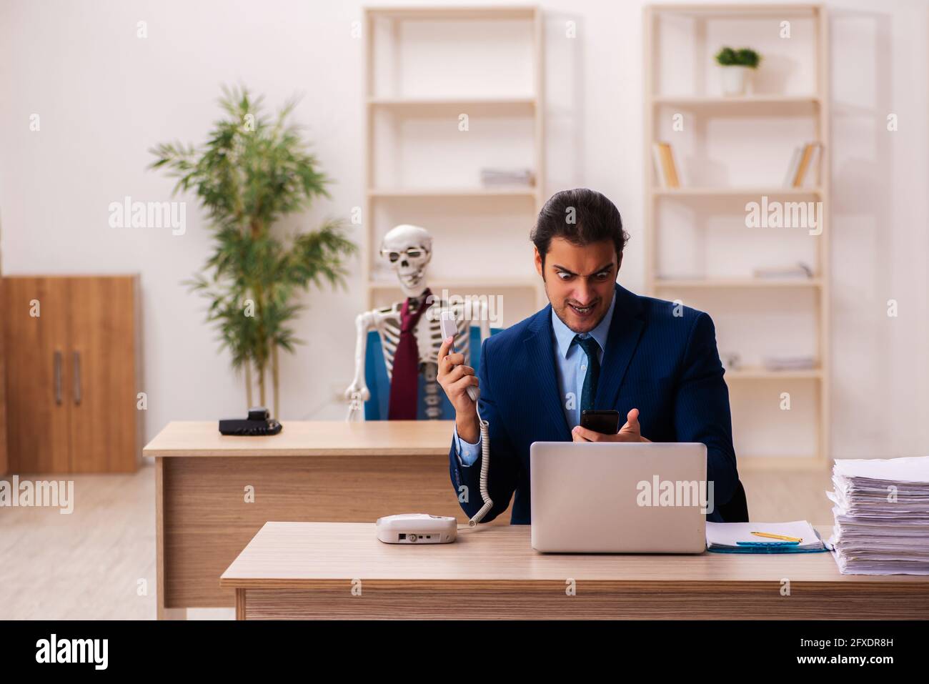 Dead employee working in the office in funny concept Stock Photo - Alamy