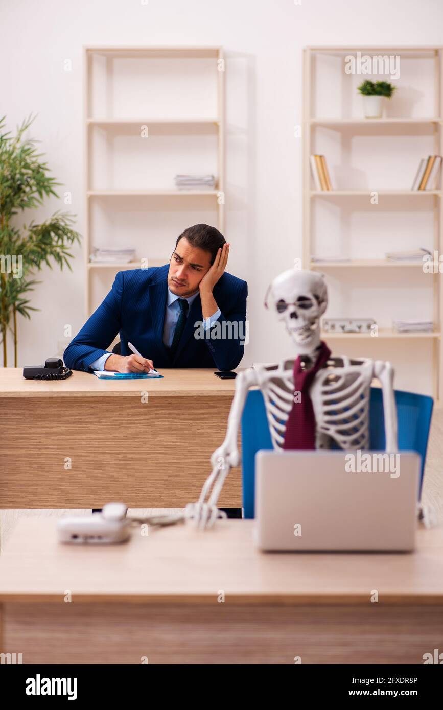 Dead employee working in the office in funny concept Stock Photo - Alamy
