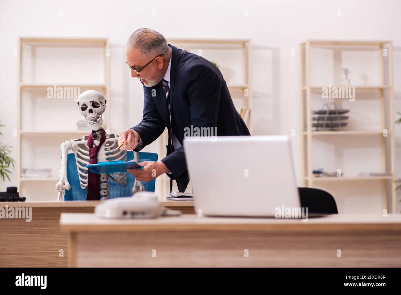 Dead employee working in the office in funny concept Stock Photo - Alamy