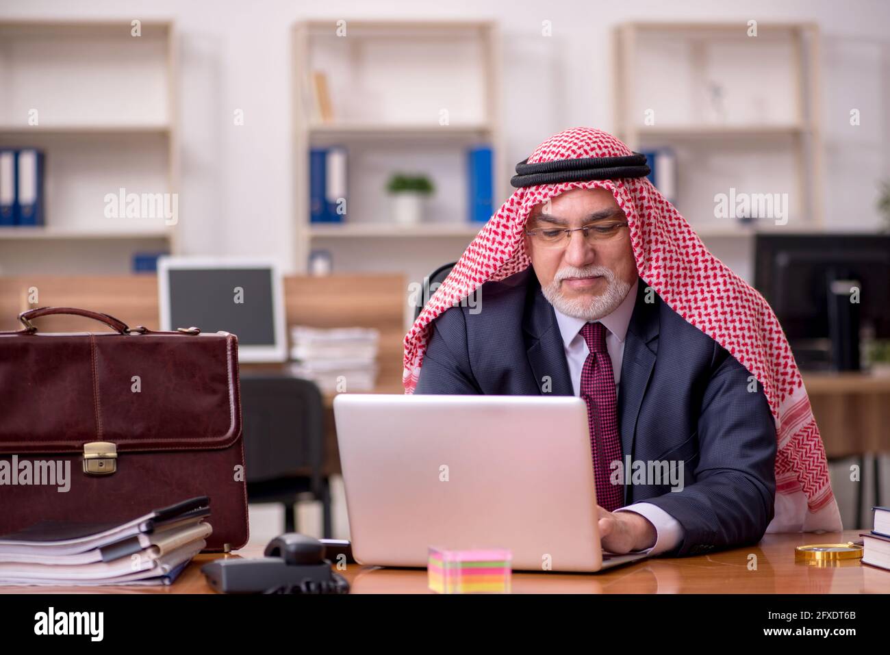 Old male arab employee sitting at workplace Stock Photo - Alamy