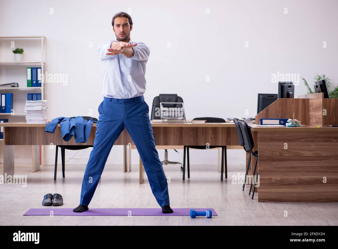 Young employee doing sport exercises during break Stock Photo - Alamy