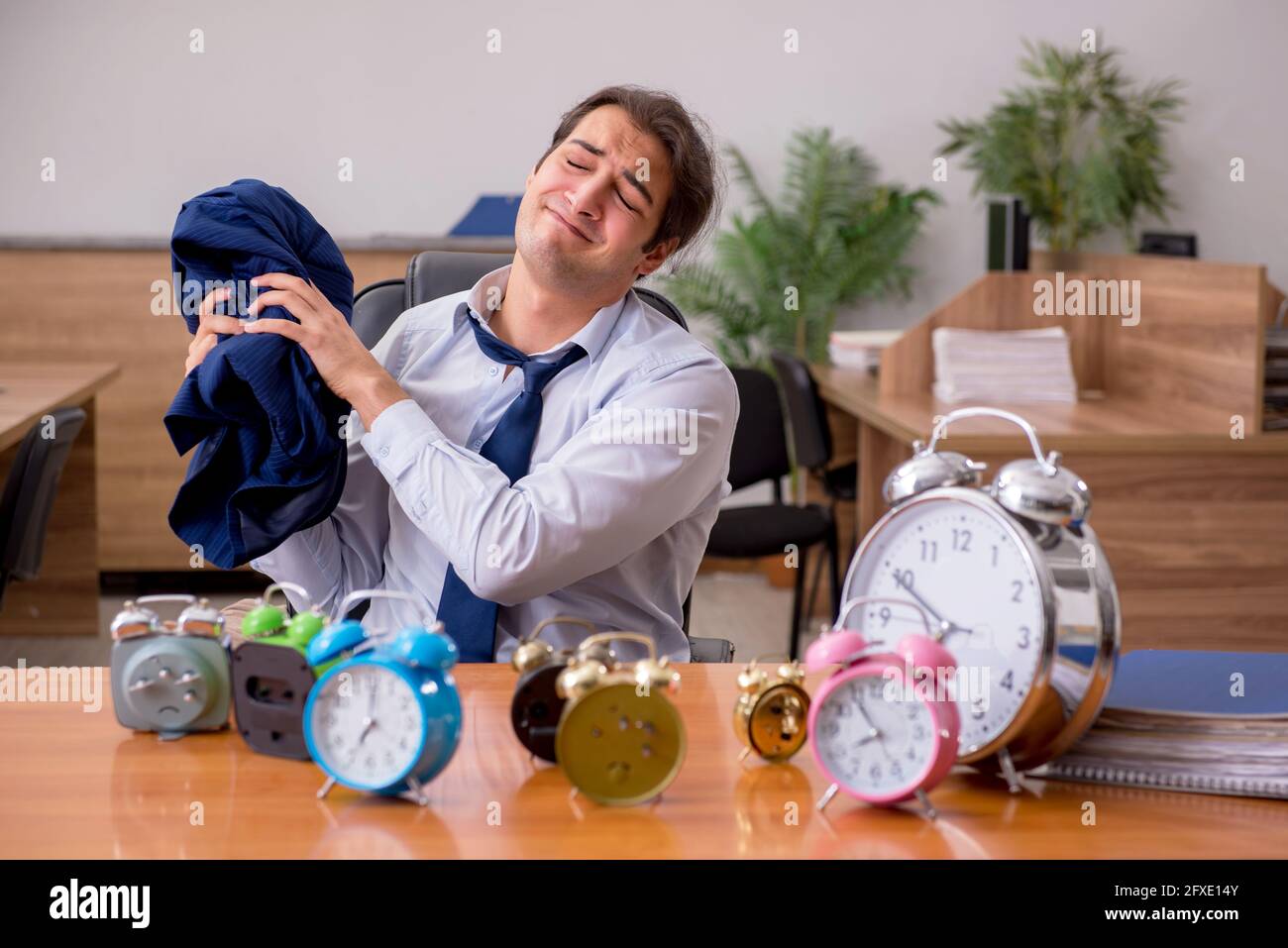 Young businessman sleeping in the office in time management concept ...