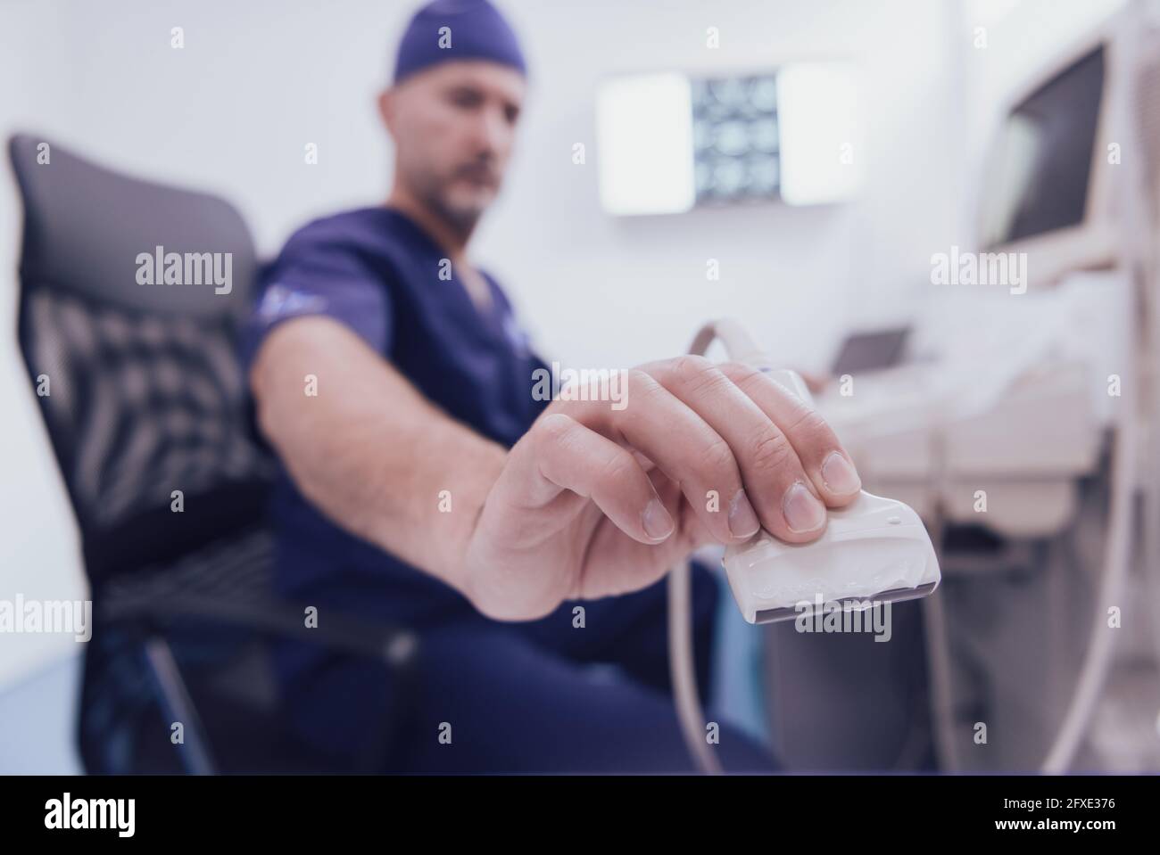doctor working at the hospital operating ultrasound scanning machine ...
