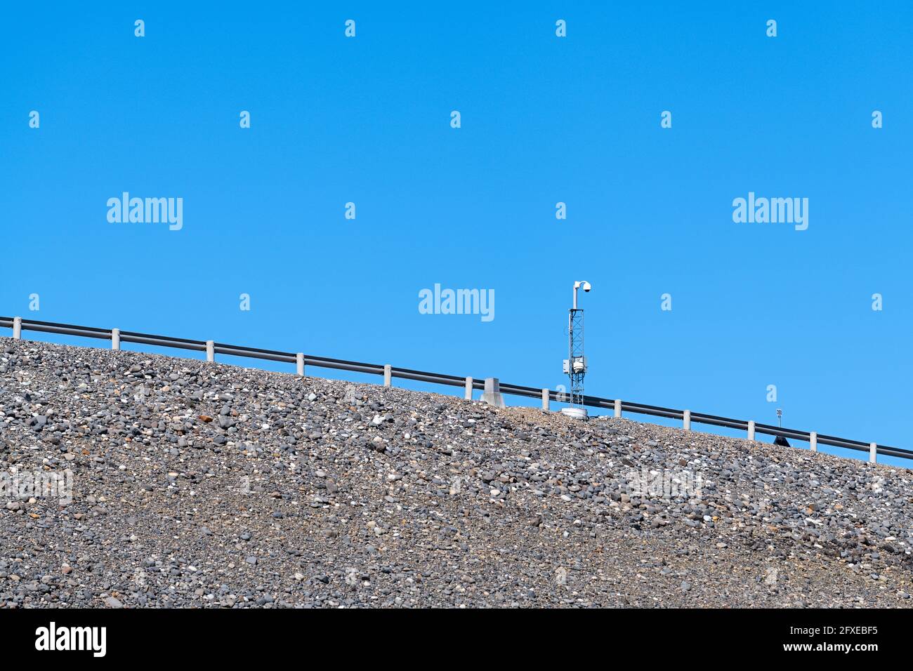 A surveillance camera by a guardrail on a highway sloping upward Stock ...