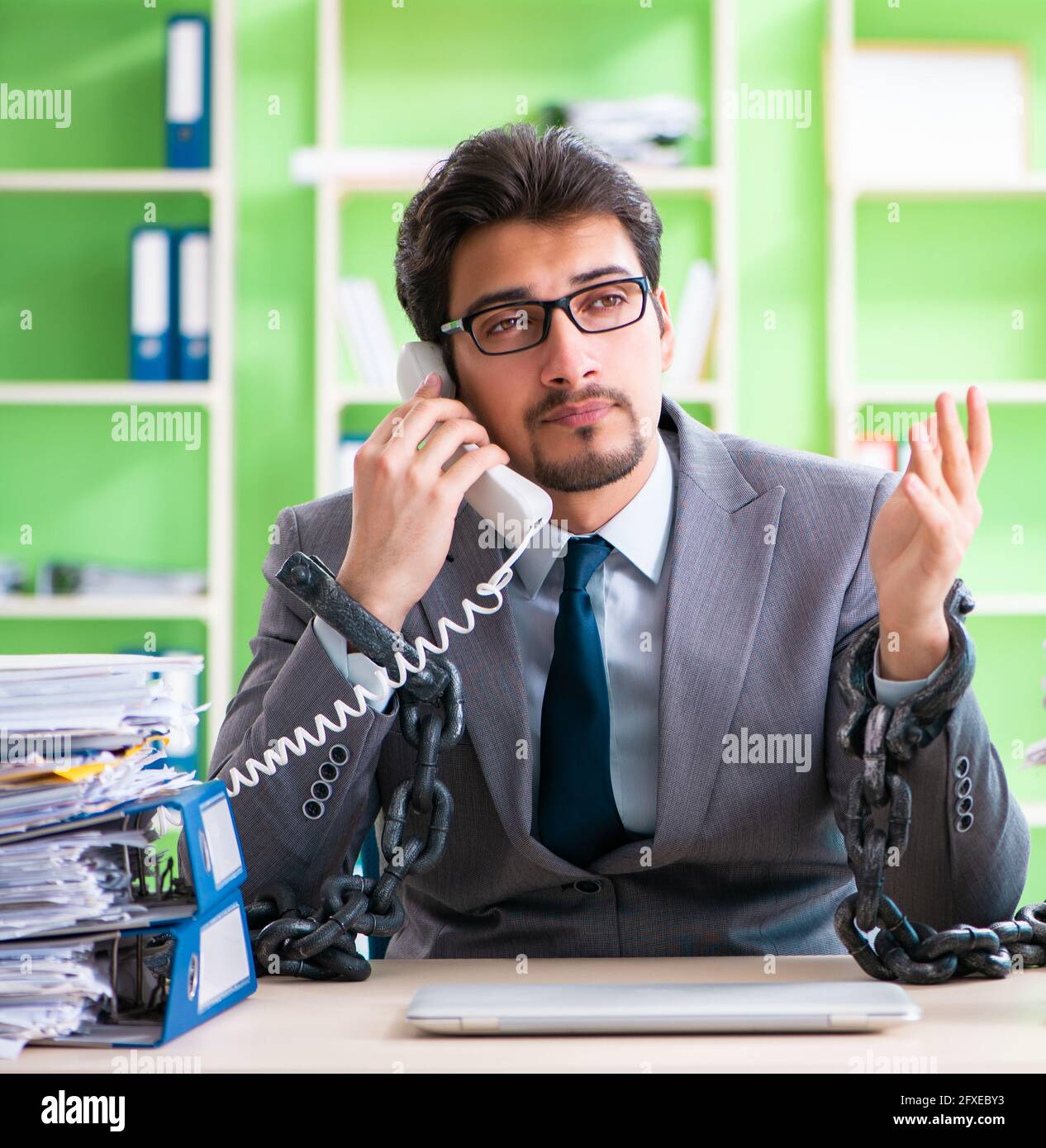 The employee chained to his desk due to workload Stock Photo - Alamy
