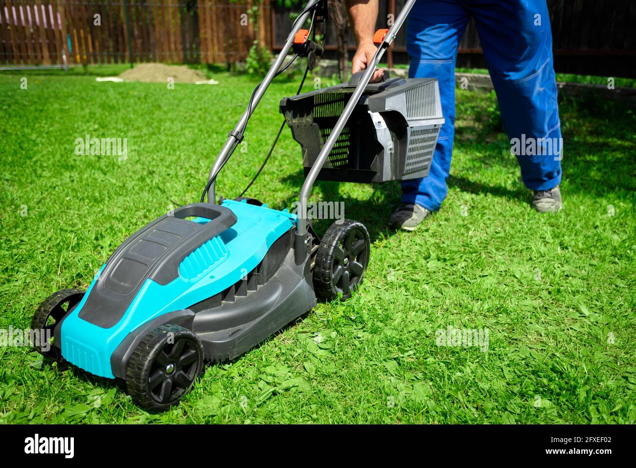 Male worker on the street working on mowing the lawn with the help of a ...