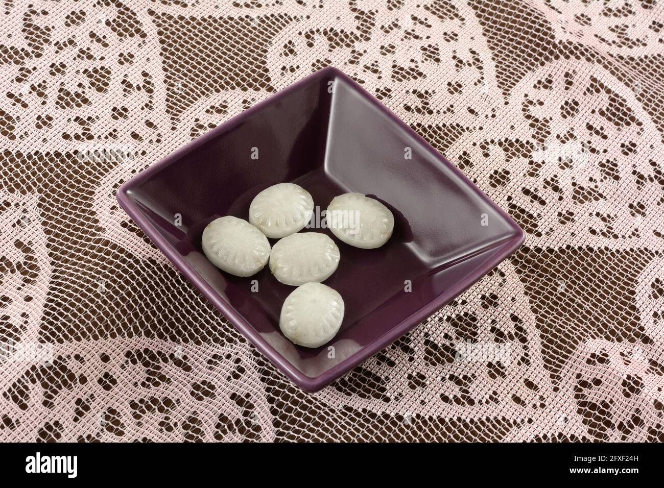 Thai mint hard candy pieces with chocolate filling in purple candy bowl ...