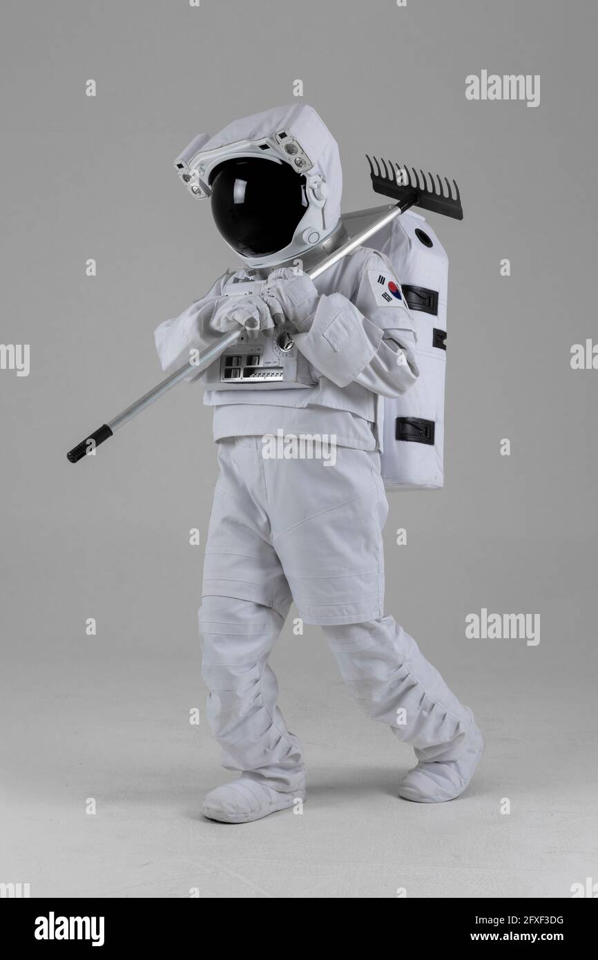 Astronaut walking holding farm equipment, white background Stock Photo ...
