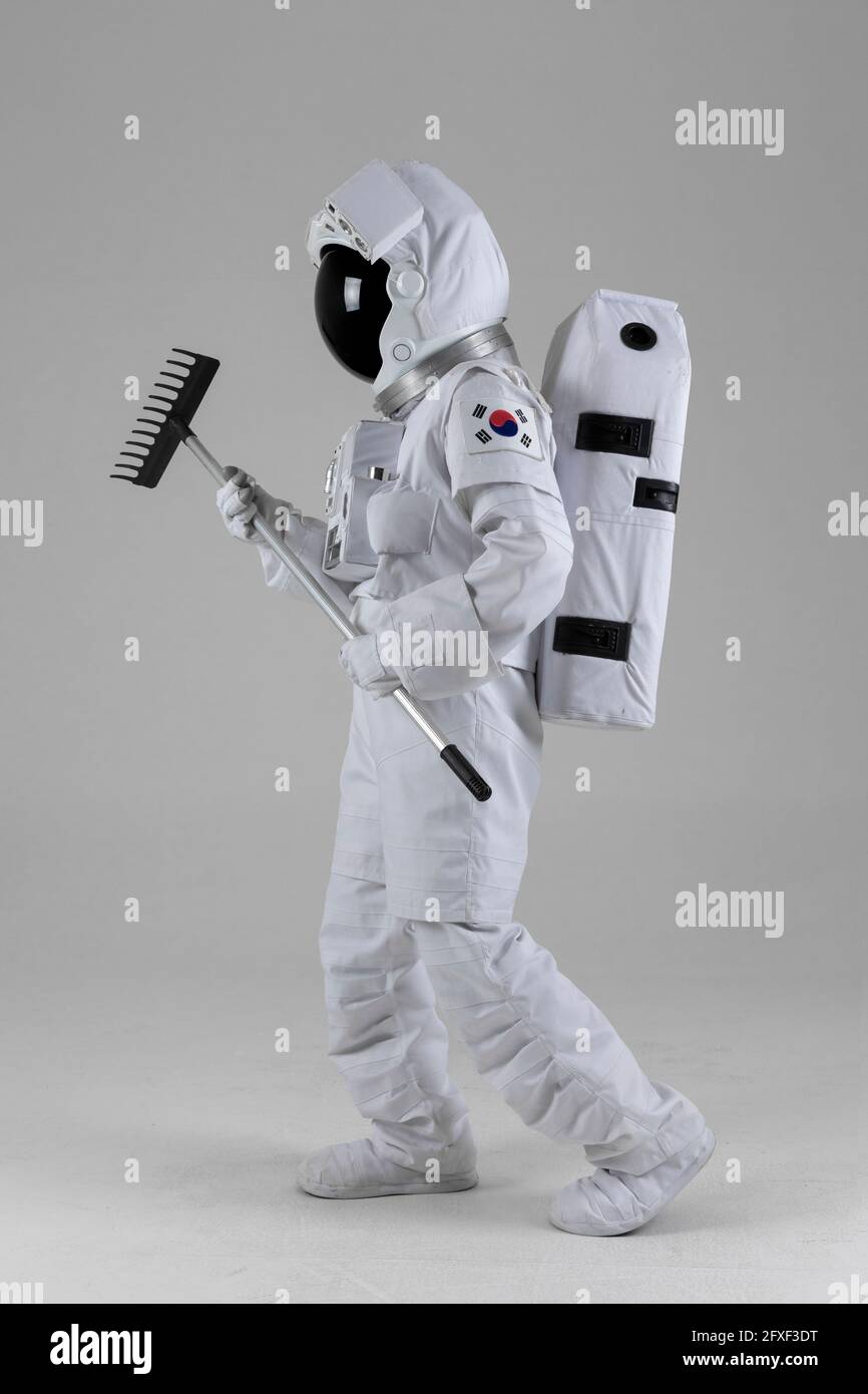 Astronaut walking holding farm equipment, white background Stock Photo ...