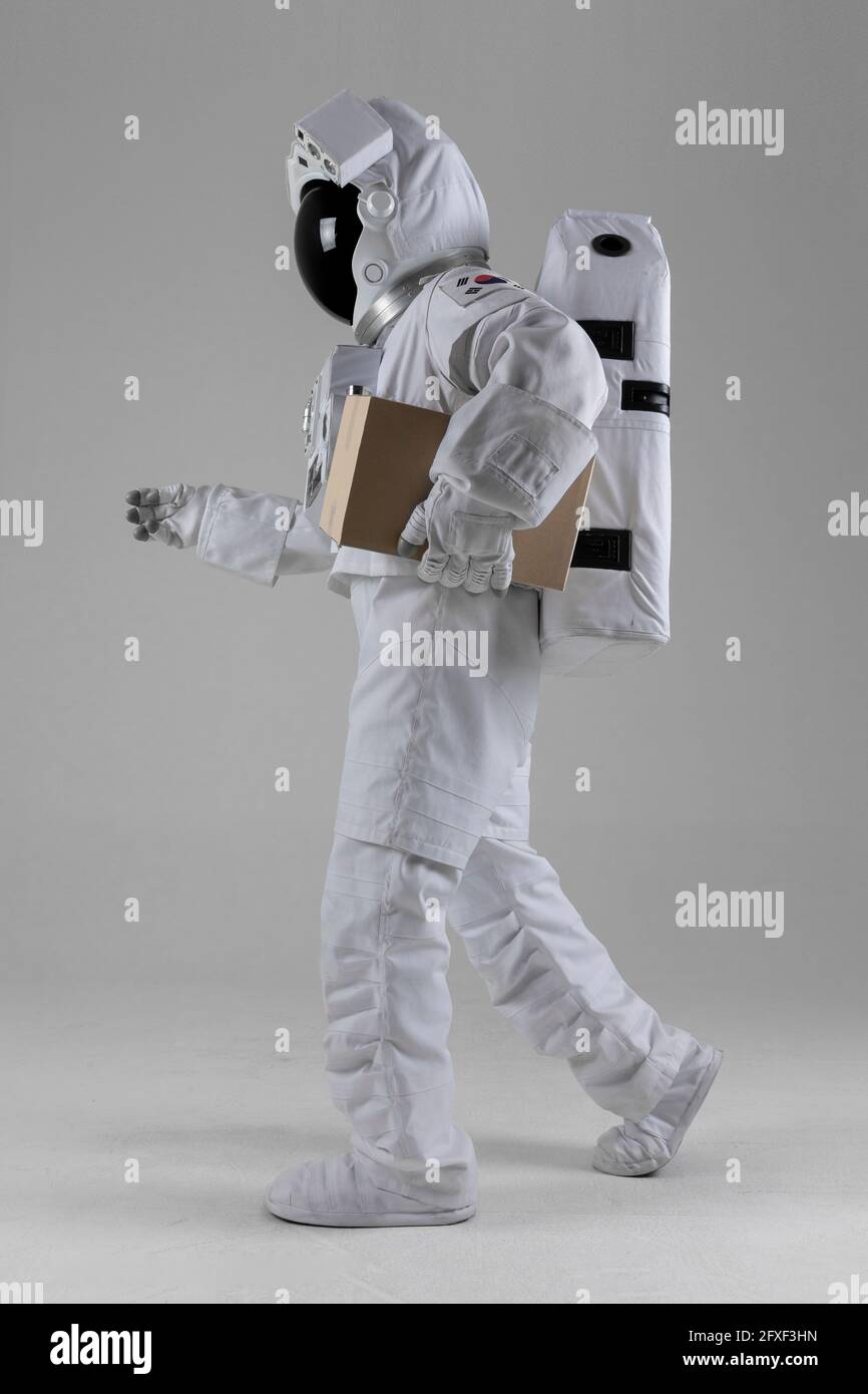 Astronaut walking holding a courier box, white background Stock Photo ...