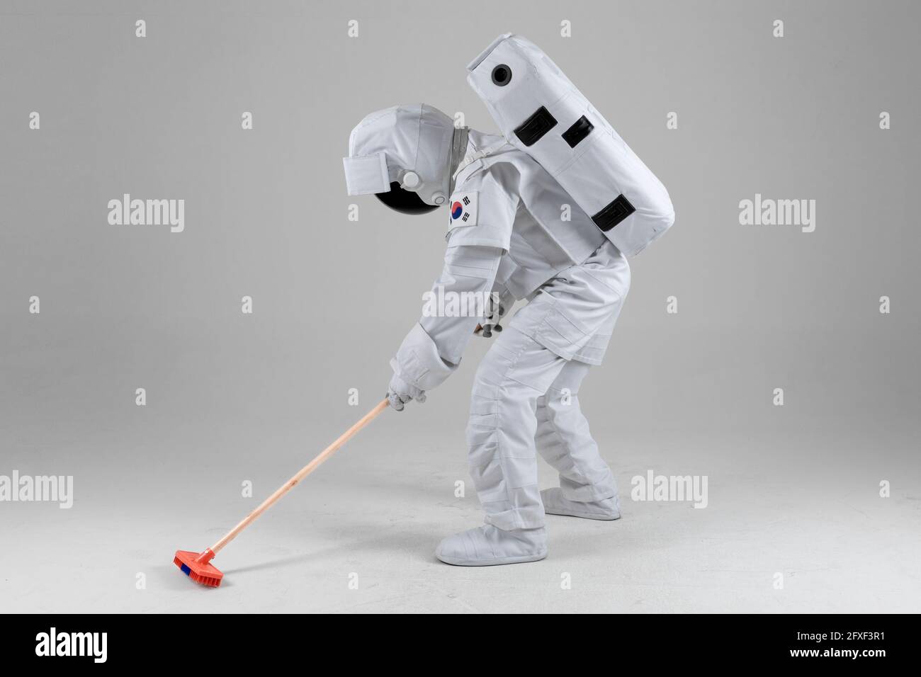 astronaut cleaning floor with brush, white background Stock Photo - Alamy