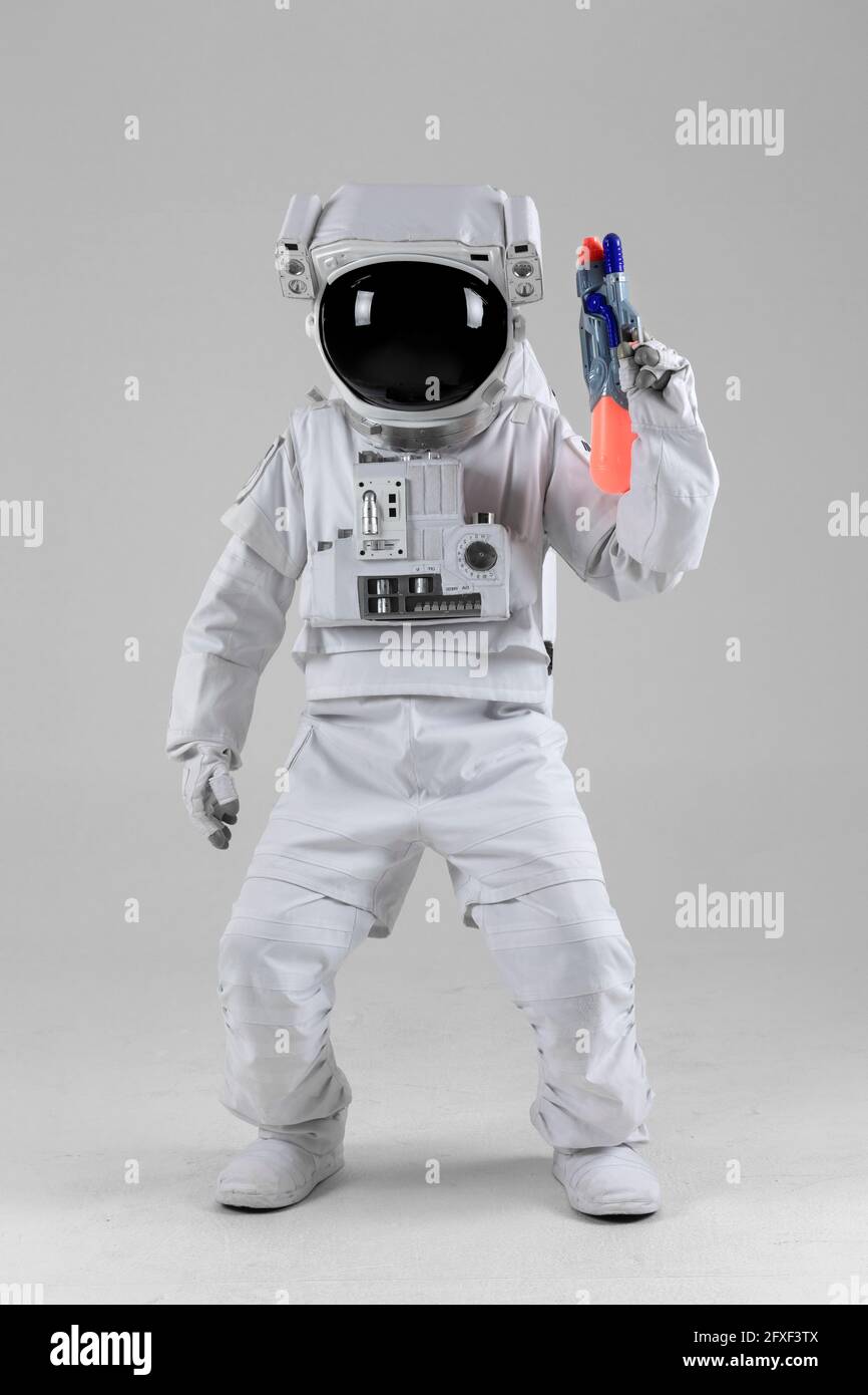 Astronaut holding a toy water gun, white background Stock Photo - Alamy