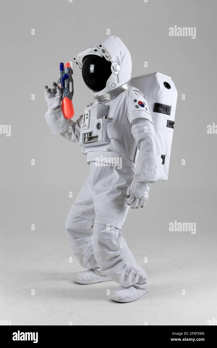 Astronaut holding a toy water gun, white background Stock Photo - Alamy