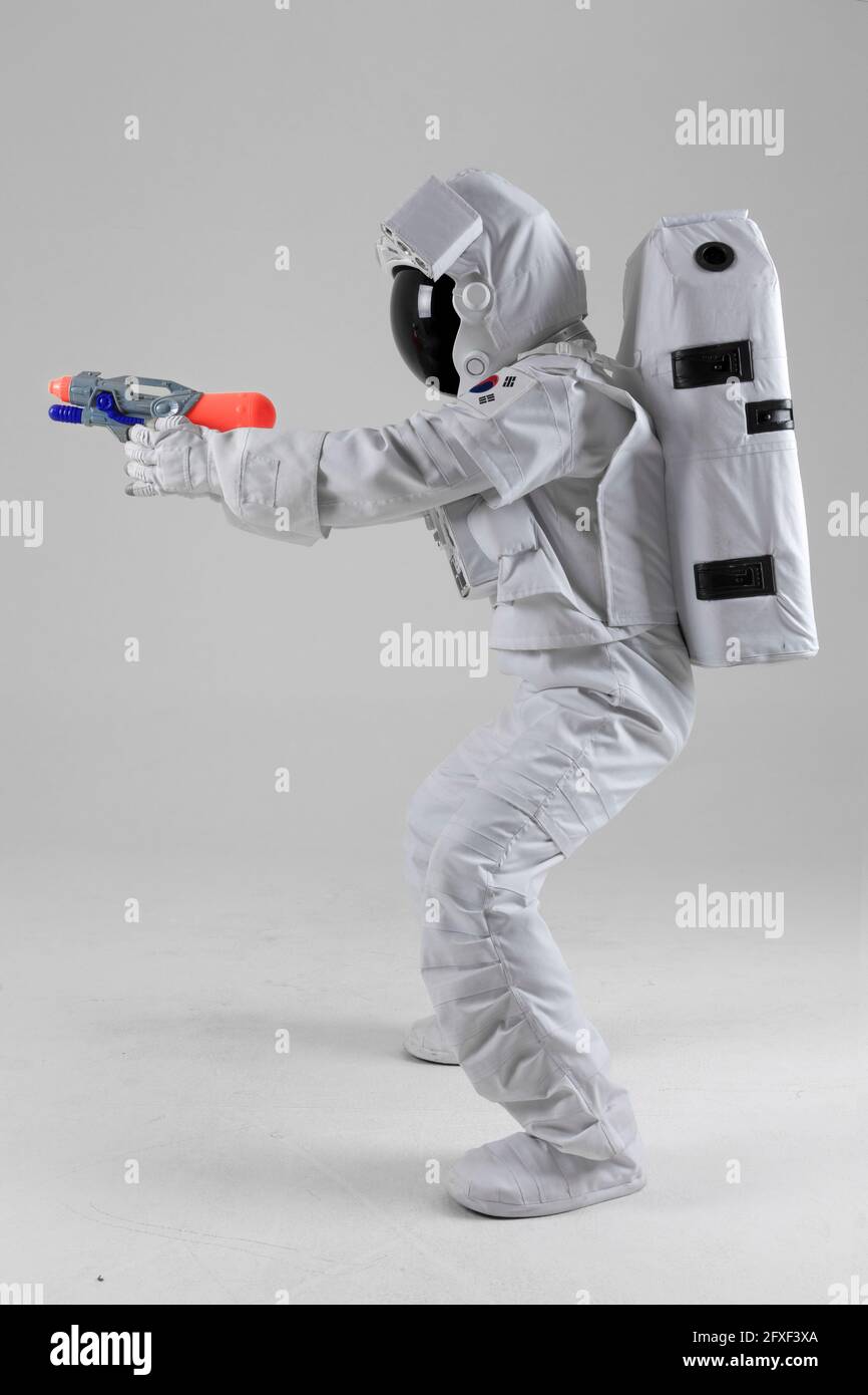 astronaut holding a toy water gun, white background Stock Photo - Alamy