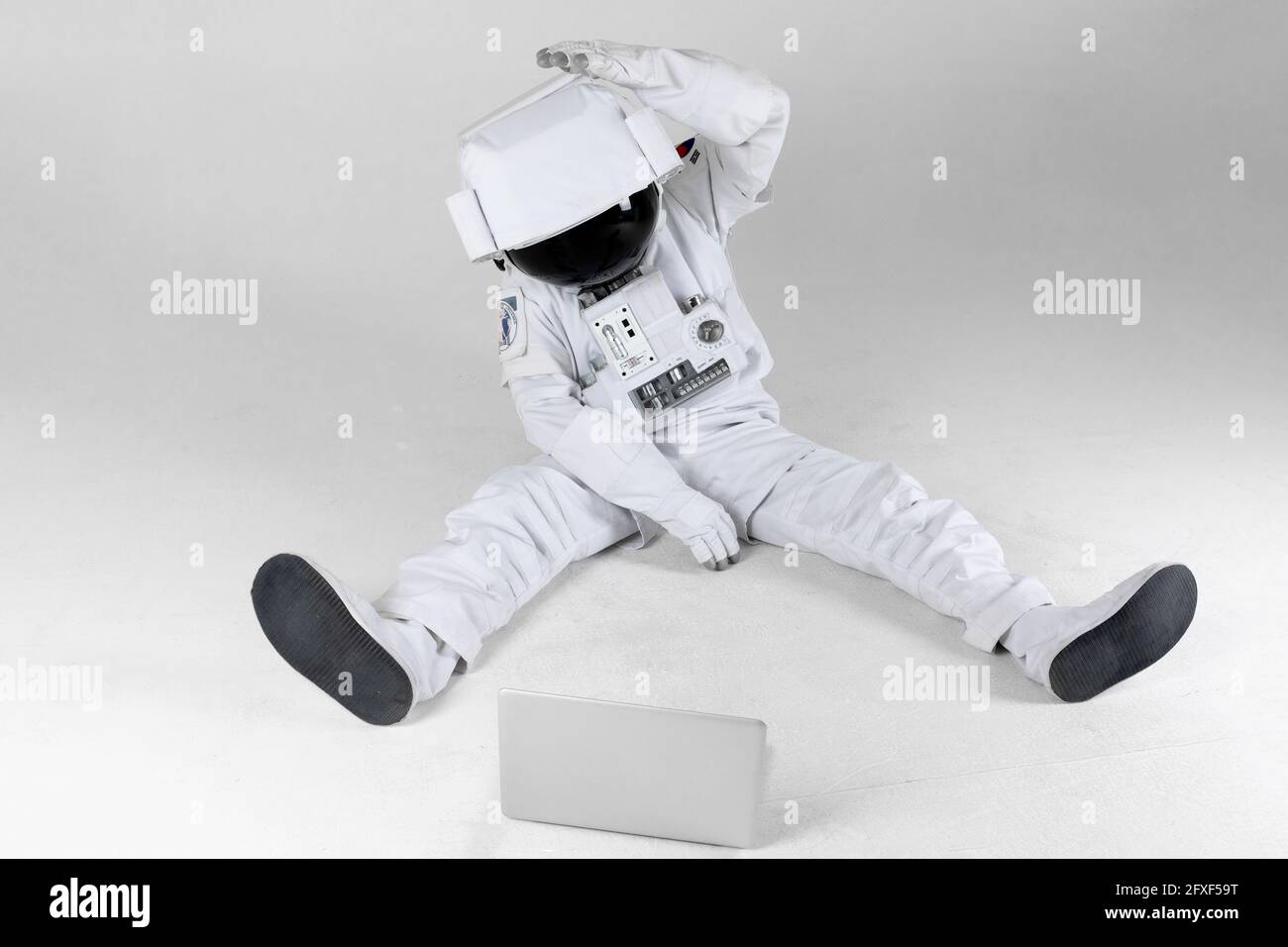 Astronaut stretching while looking at the laptop, white background ...