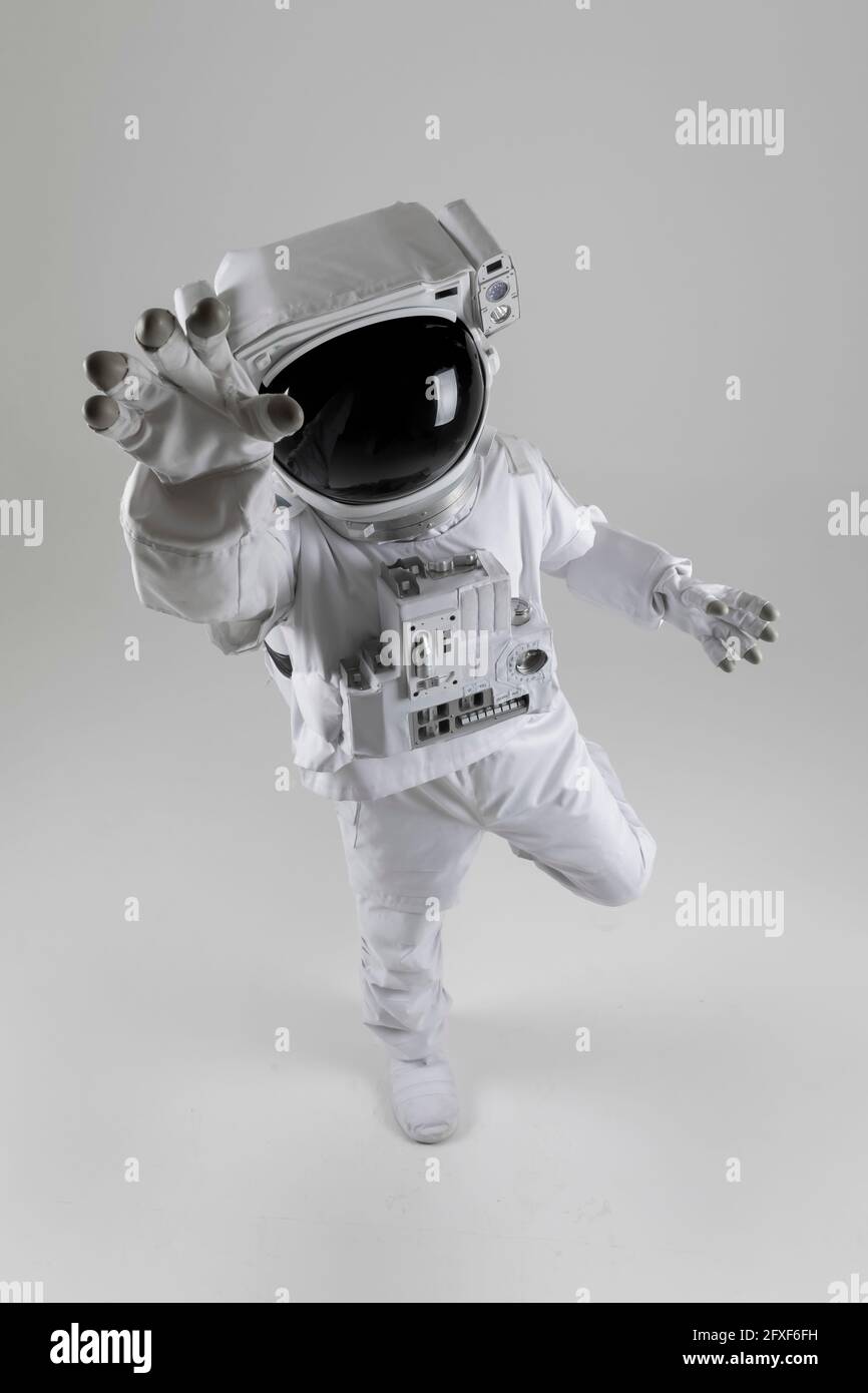 Astronaut stretching hand, white background Stock Photo - Alamy