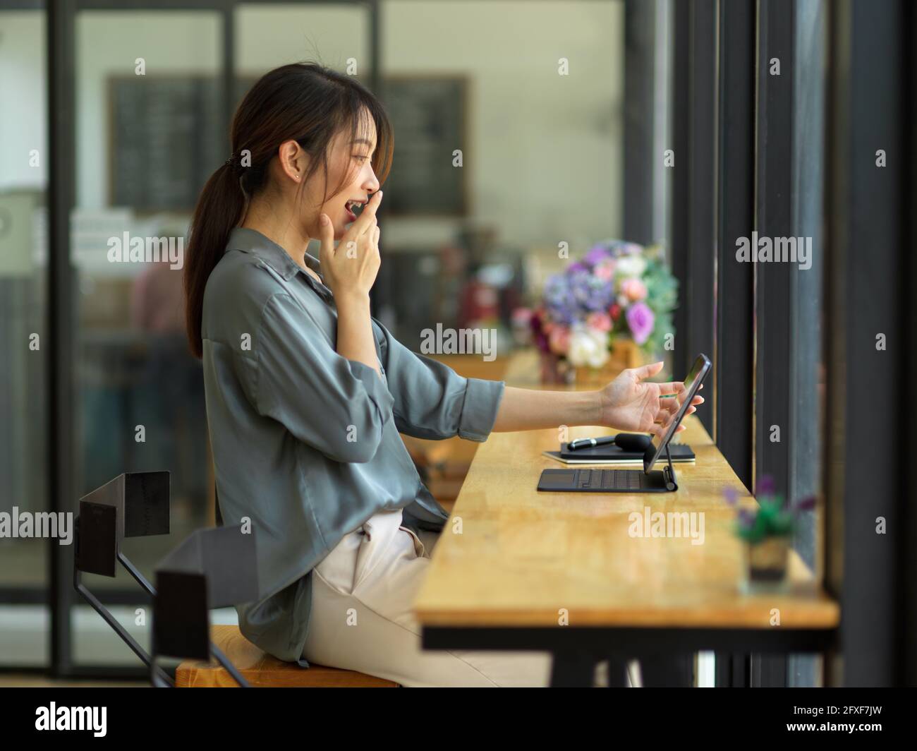 Side view of excited young female looking at digital tablet screen ...