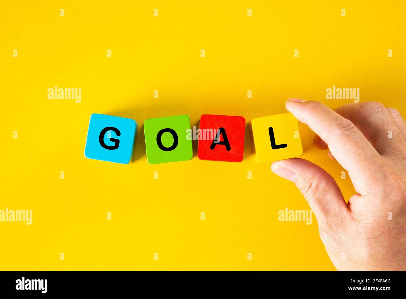 Man hand placing the wooden cubes with the word GOAL on yellow ...