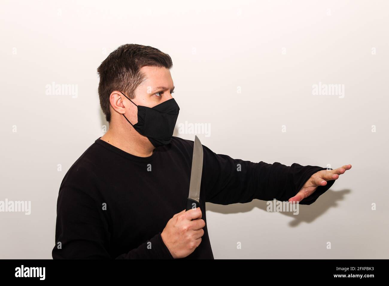 Serious Brazilian male with a face mask threatening with a knife Stock ...