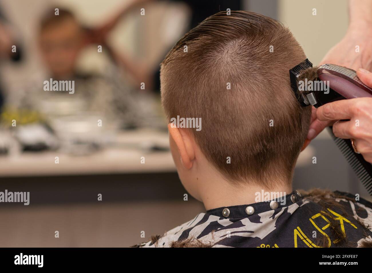Cute kid boy have hair cut, professional barber doing haircut ...