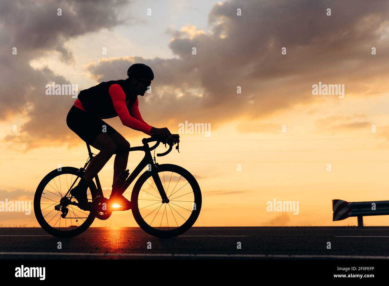 Side view of road cyclist training during amazing sunset Stock Photo ...