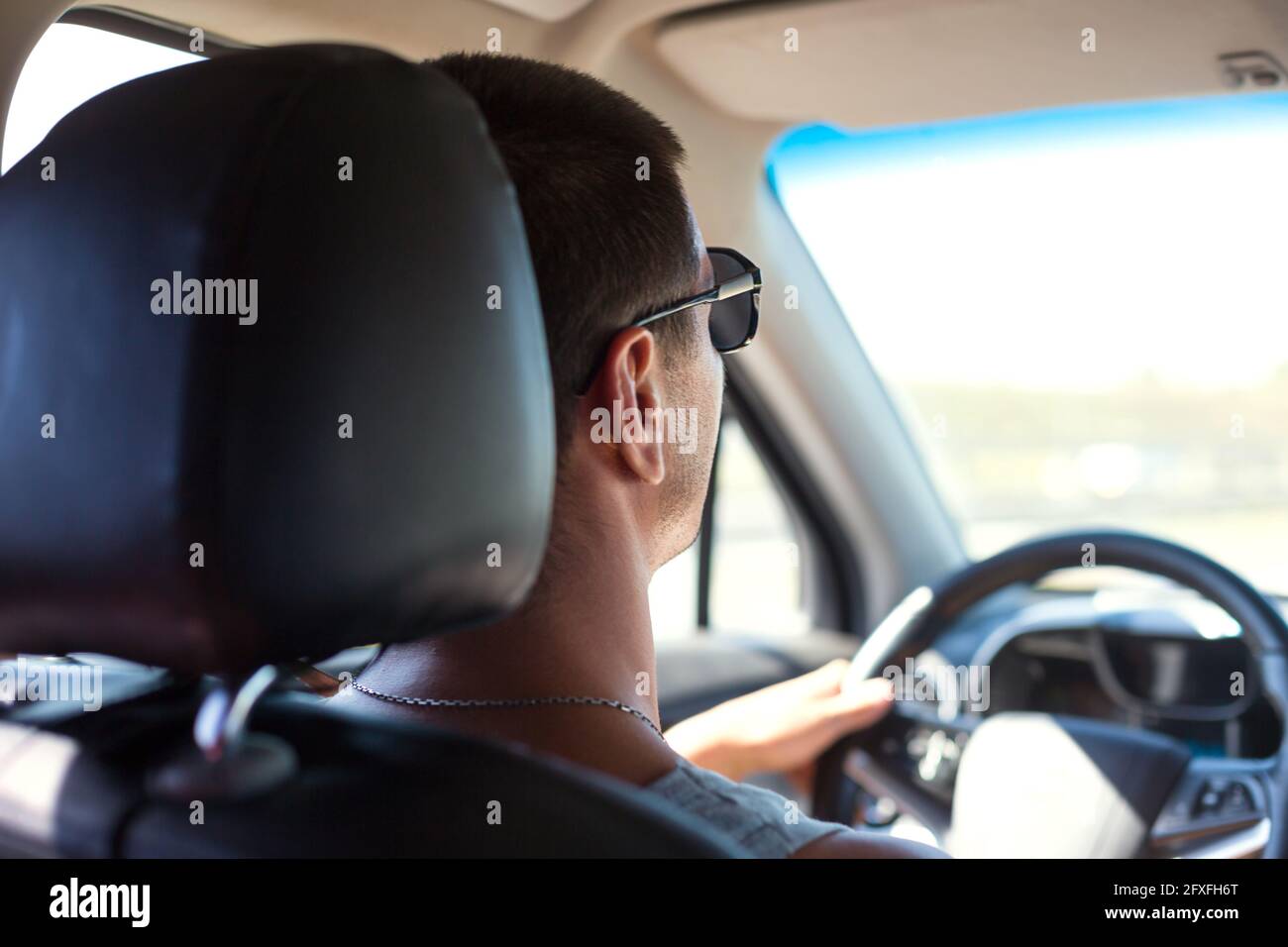 A man with dark glasses is driving a car. Road safety, traffic rules ...