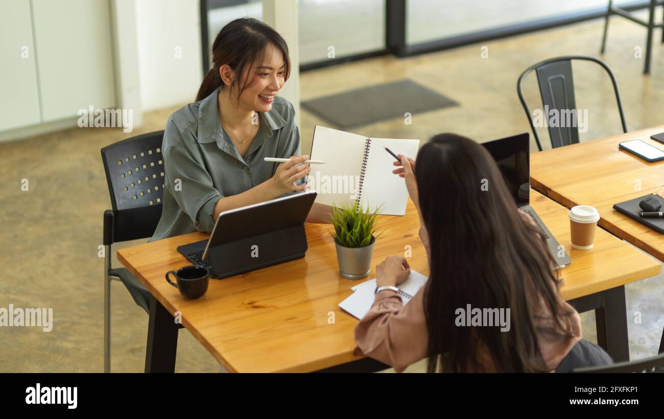Top view of two female office workers consulting their work with ...