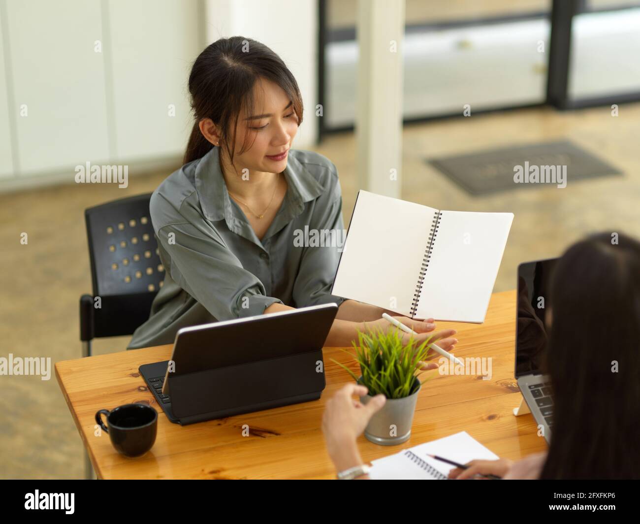Top view of two female office workers consulting their work with ...