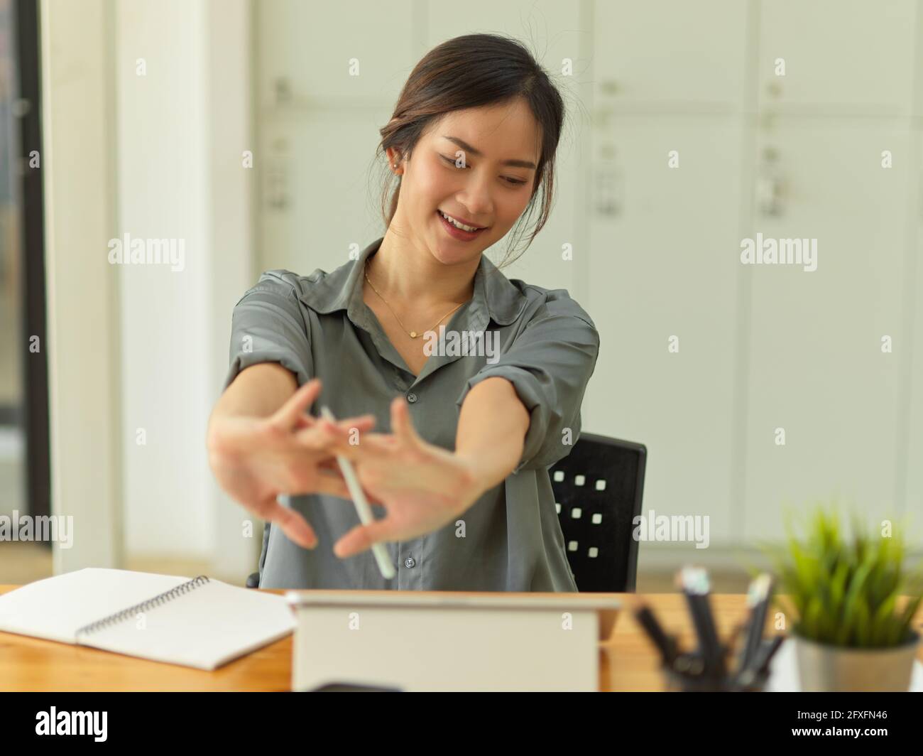 Half-length portrait of female office worker relaxing and stretching ...